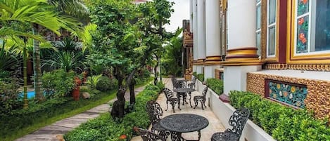 Um pátio com calçada pavimentada, área de estar externa e vegetação exuberante.