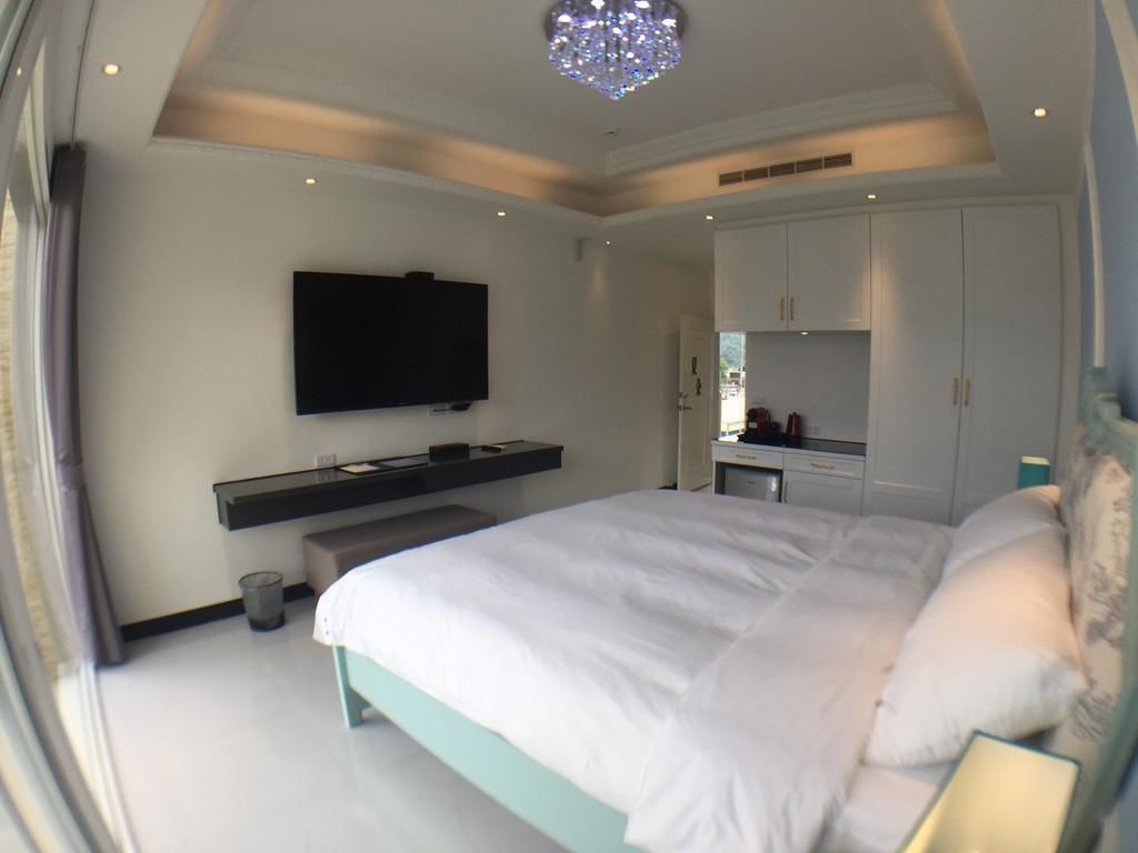 Quarto moderno com uma cama grande, televisão de tela plana na parede e um banco embutido sob a cama.