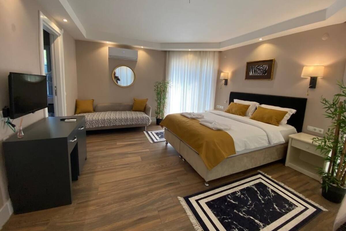 Quarto de hotel moderno com cama, sofá, televisão e escrivaninha.