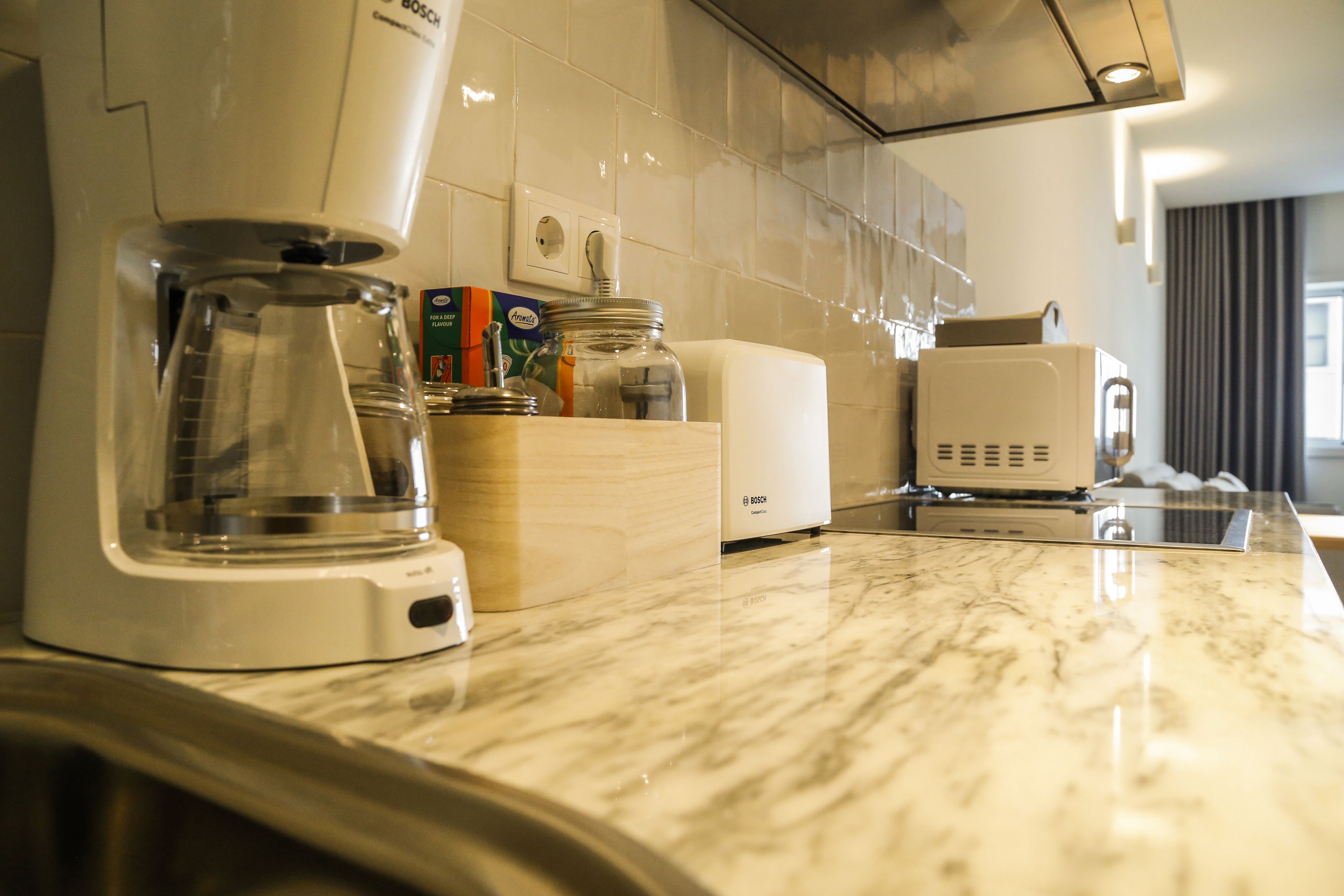 Uma cozinha com cafeteira Bosch, torradeira e liquidificador em bancada de mármore.