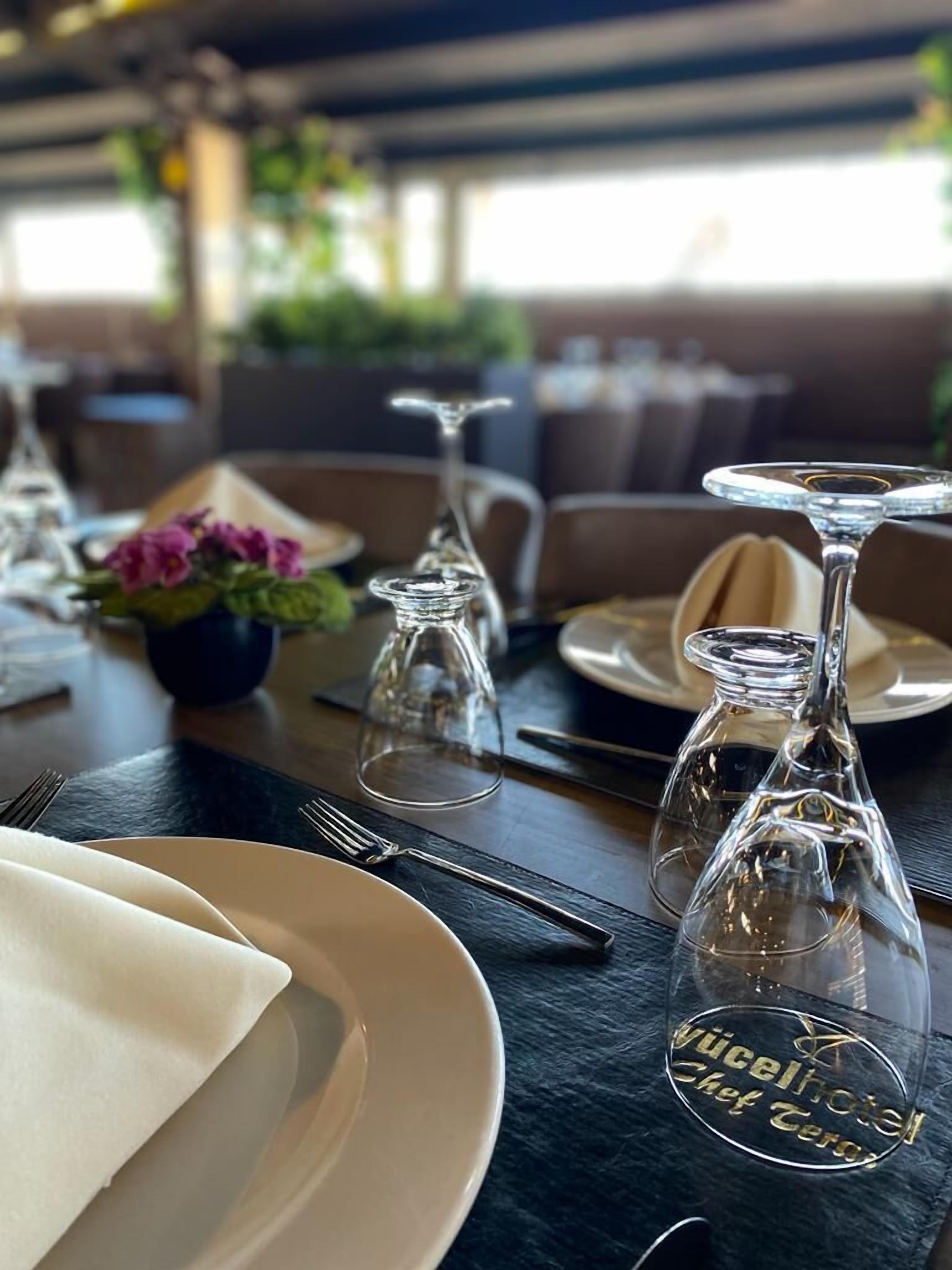 Uma mesa de jantar posta com pratos, talheres e copos de vinho.