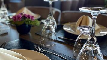 Uma mesa de jantar posta com pratos, talheres e copos de vinho.