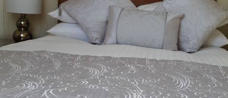 Cama bem arrumada com colcha estampada e dois travesseiros decorativos.