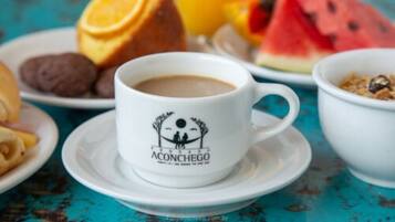 Uma mesa posta para o café da manhã, com uma xícara de café, fatias de laranja, biscoitos e uma fatia de melancia.