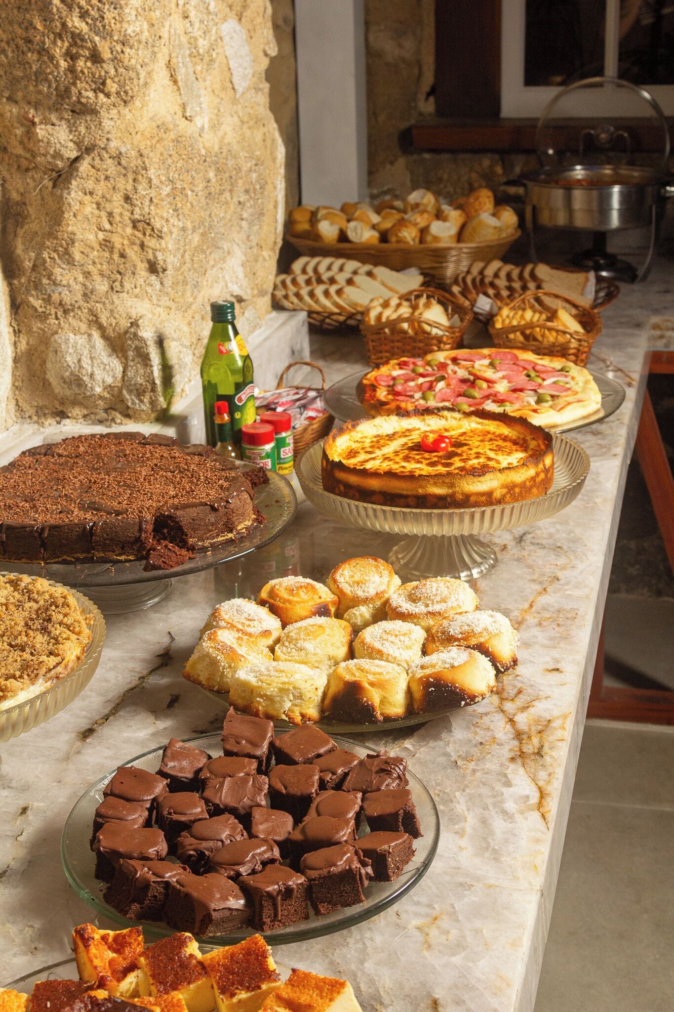 Um buffet com diversos pães e sobremesas.
