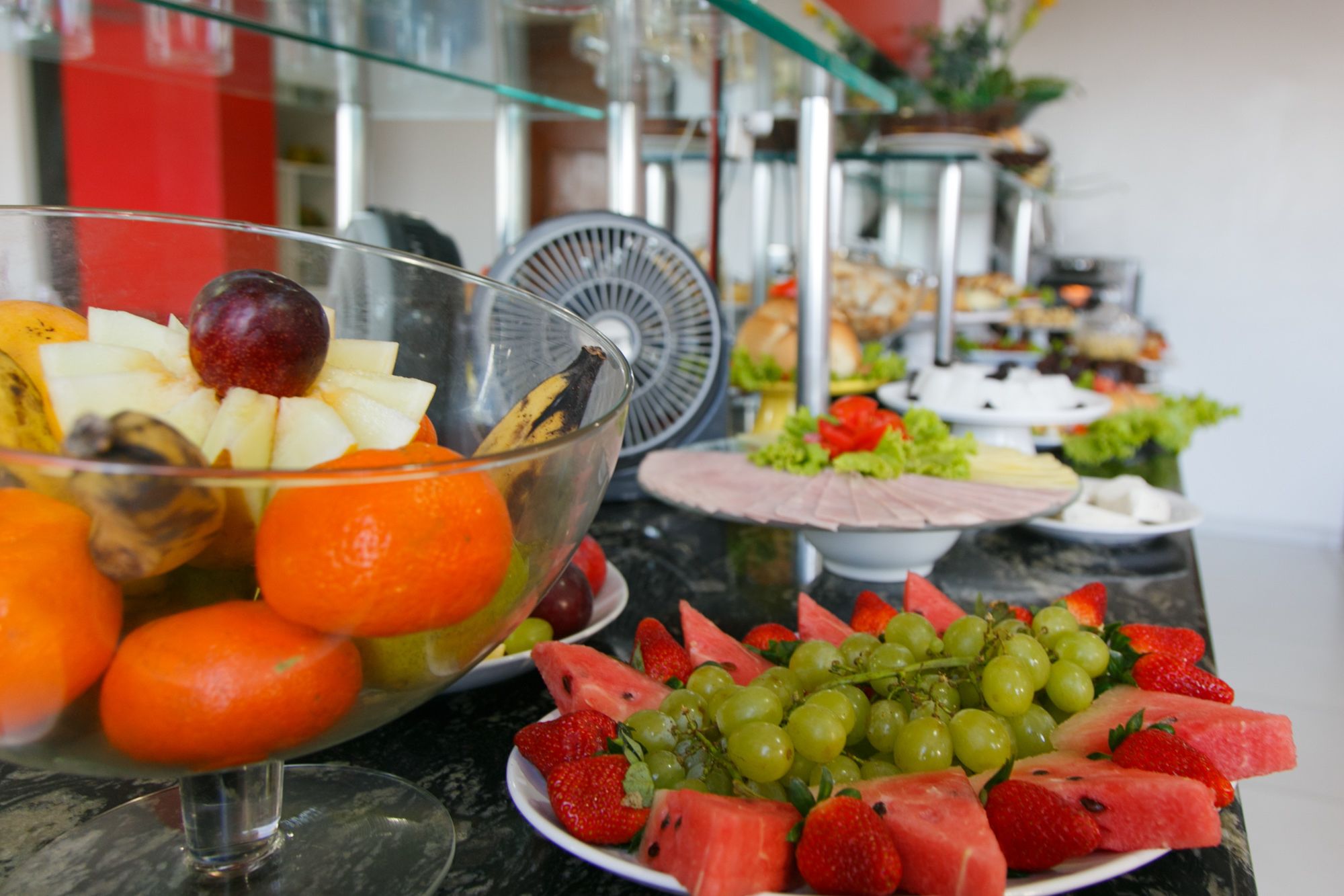 Uma mesa de buffet com diversas frutas e uma tigela de frutas mistas.