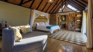 Um quarto aconchegante com uma cama, um sofá, uma parede de pedra e teto de madeira.