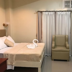Quarto de hotel com uma cama, uma cadeira e uma cortina.