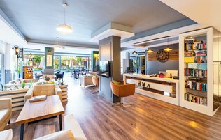 Uma sala de estar moderna com piso de madeira, sofás, uma mesa de centro e uma estante de livros.
