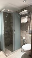Um banheiro moderno com chuveiro em gabinete de vidro, vaso sanitário e porta-toalhas.