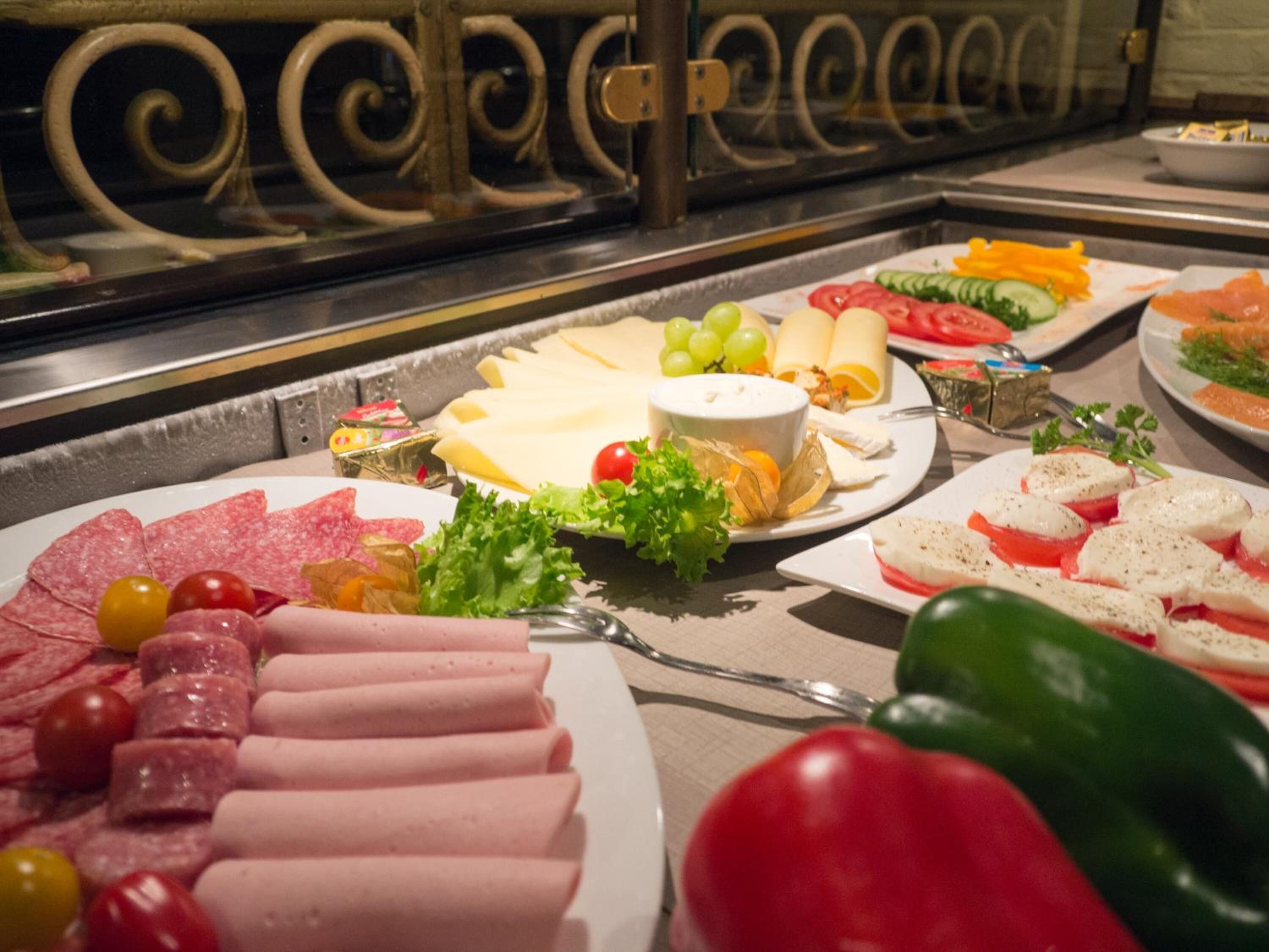 Buffet com diversos alimentos, incluindo carnes, queijos e legumes.