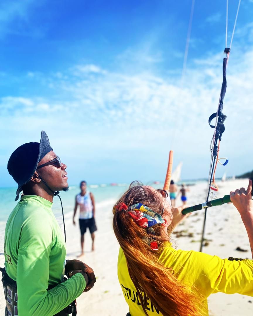 Cena de praia com uma pessoa em cadeira de rodas e outra segurando um balão.
