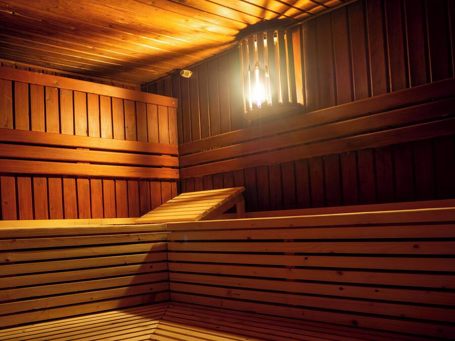 Uma sauna de madeira com bancos e teto inclinado.