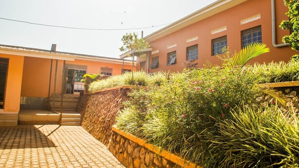 Um pátio com muro de pedra, degraus que levam a uma porta e um edifício com janelas e porta.