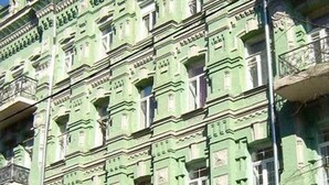 Um edifício com vários andares e detalhes arquitetônicos elaborados, incluindo varandas e molduras decorativas.
