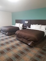 Quarto de hotel com duas camas, balcão de recepção e televisão presa à parede.