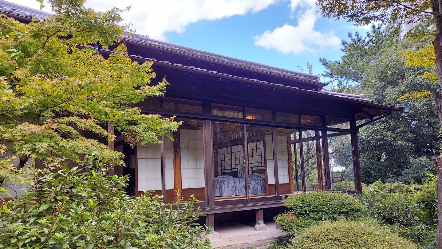 Um edifício japonês tradicional com estrutura de madeira, grandes janelas e um jardim.