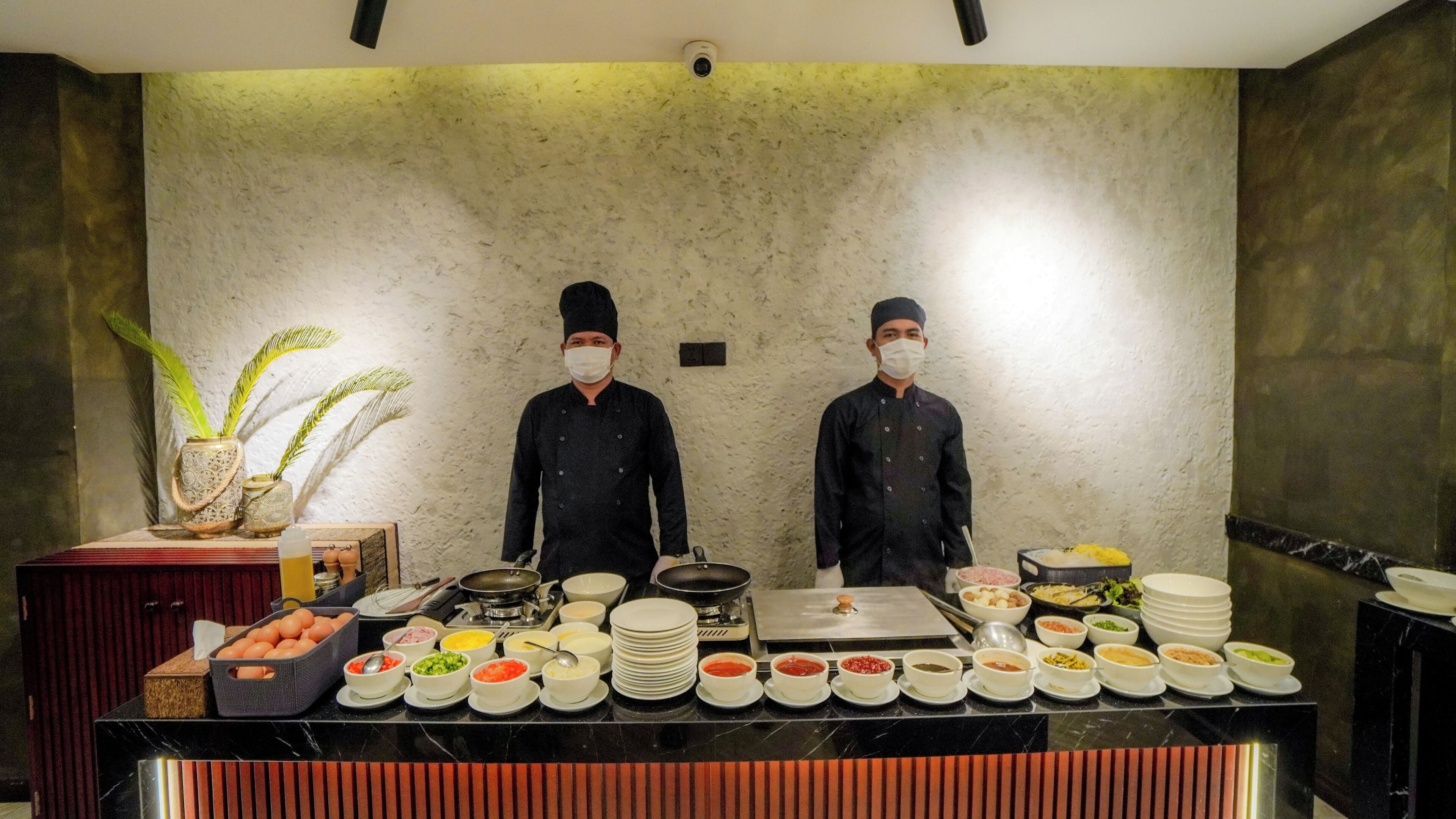 Disposição de buffet com diversos pratos e uma planta decorativa.