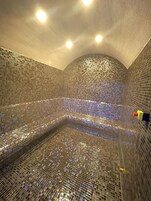 Quarto com soalho e paredes em azulejo, teto curvo e iluminação embutida.