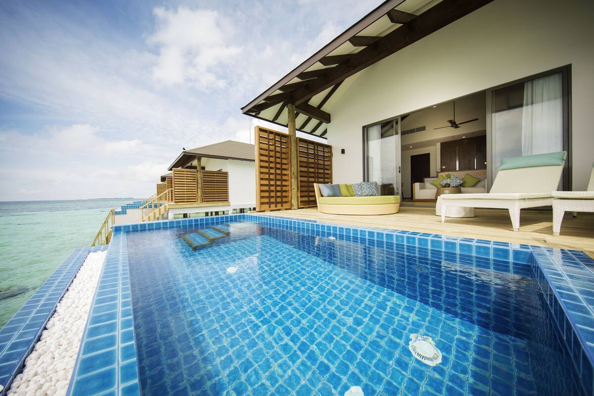 Uma piscina infinita com vista desobstruída para o oceano, área de estar coberta ao ar livre e interior moderno com ventilador de teto.