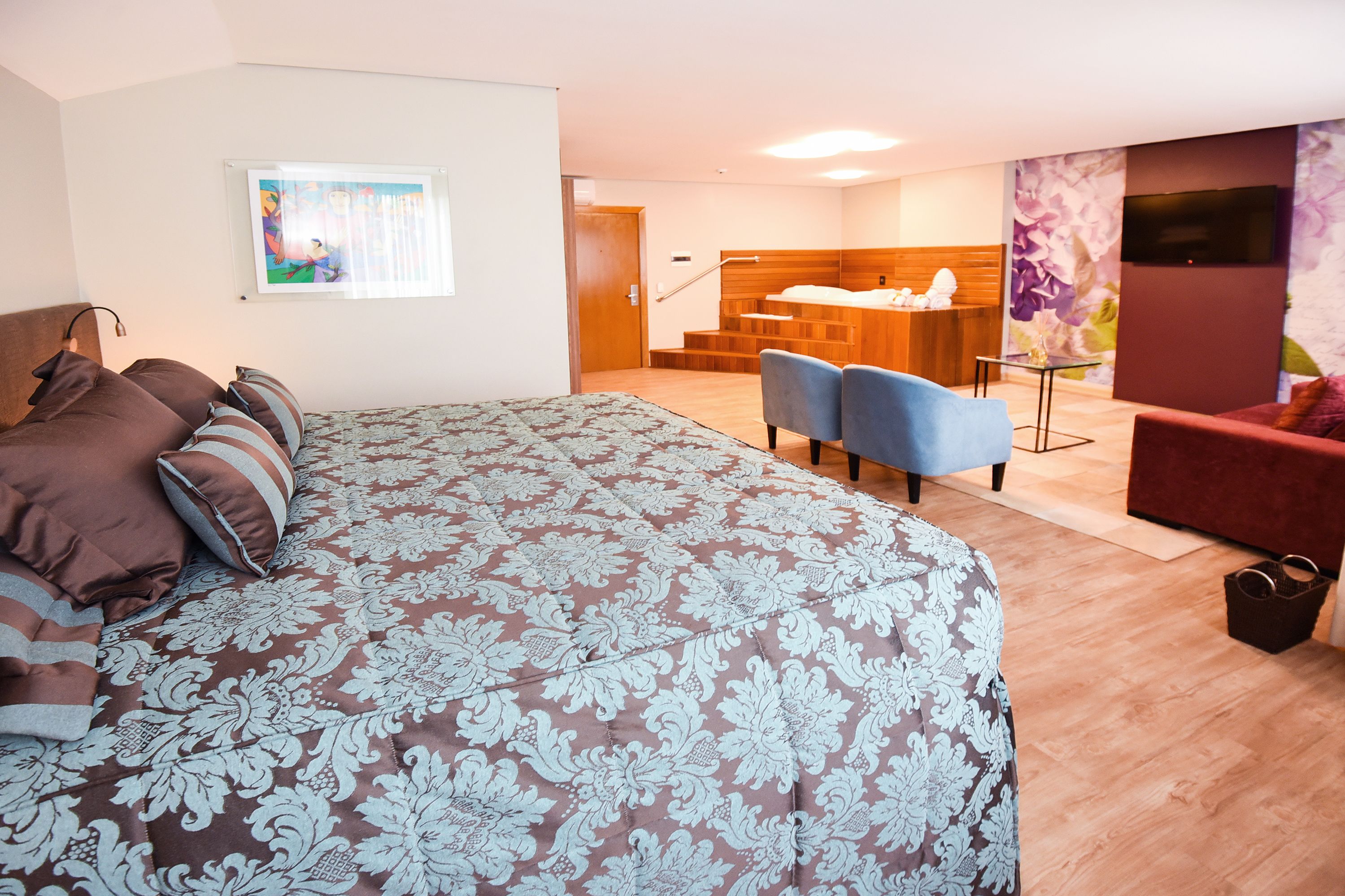 Quarto com cama grande, escrivaninha e televisão.