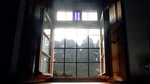 Quarto com uma grande janela que oferece vista para uma paisagem montanhosa.