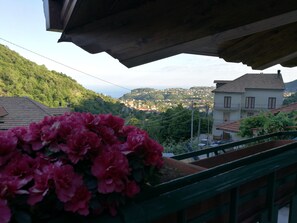 Uma varanda com vista para uma vila no sopé da colina e um edifício com telhado de azulejos.