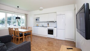 Cozinha moderna com armários brancos, micro-ondas, forno e área de refeições com mesa e cadeiras.