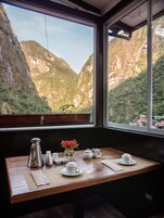 Uma mesa com vista para uma paisagem montanhosa através de uma janela.