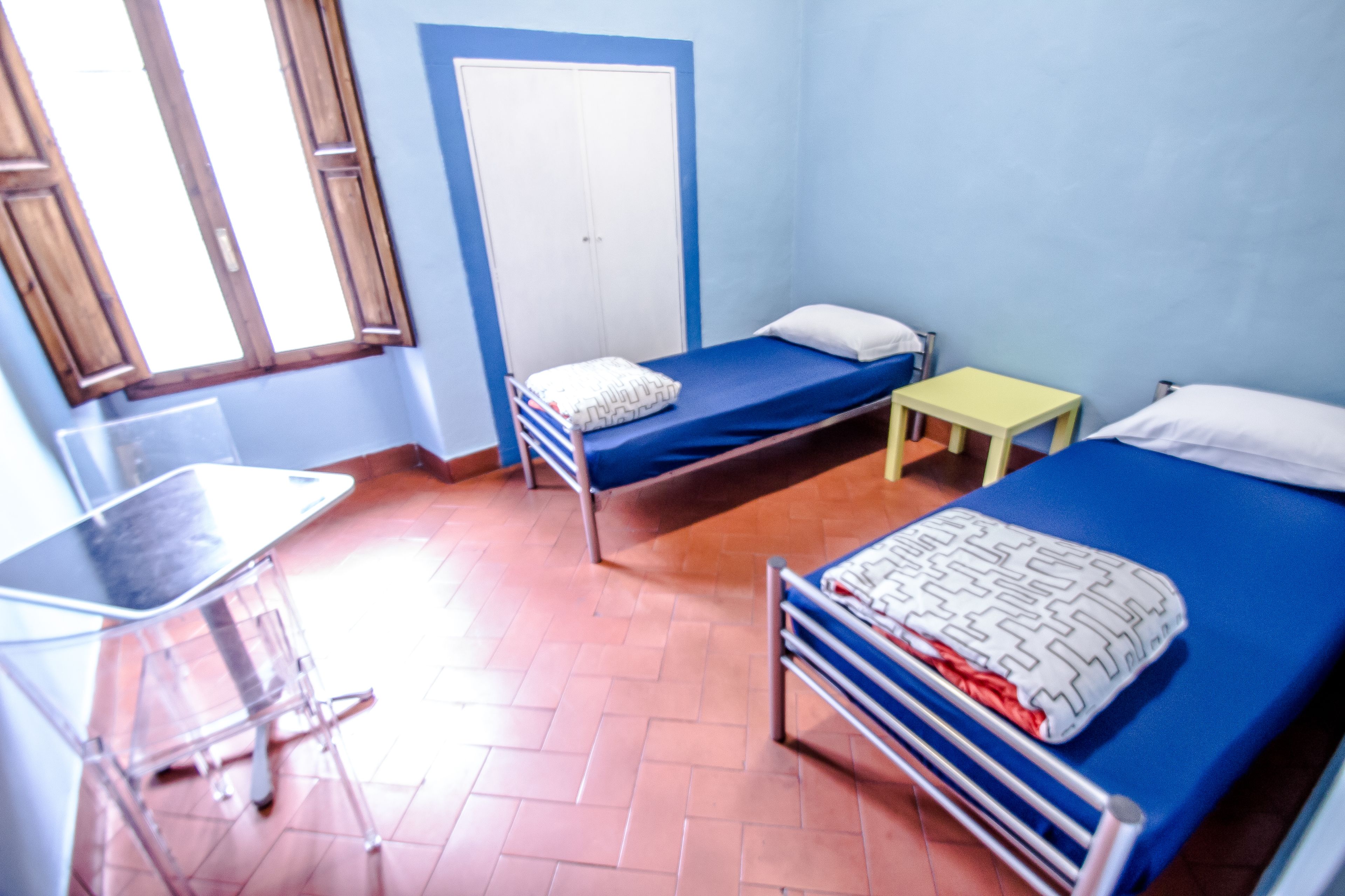 Quarto com cama, uma mesinha, uma cadeira e um guarda-roupa.