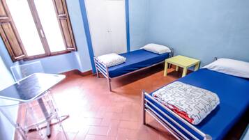 Quarto com cama, uma mesinha, uma cadeira e um guarda-roupa.