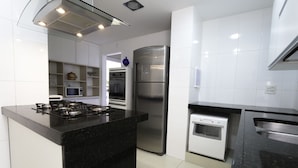Uma cozinha moderna com ilha central, eletrodomésticos de aço inoxidável e armários brancos.