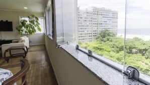 Um quarto com uma janela grande, uma planta, um sofá e uma televisão na parede.