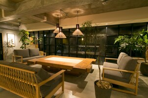 Uma sala de estar moderna com um sofá, poltronas, uma mesa de centro de madeira e luminárias pendentes.