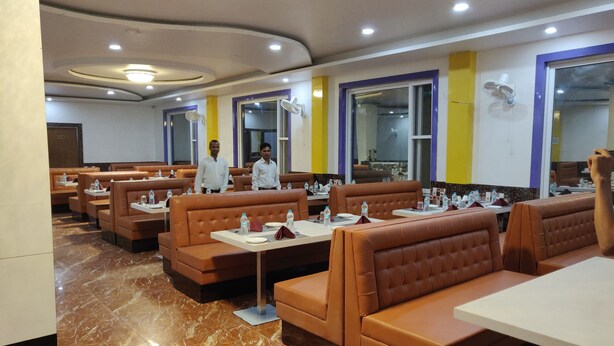Restaurante com assentos em cabines, piso de mármore e ventiladores de teto.