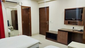 Quarto de hotel com duas camas, televisão, escrivaninha e guarda-roupa.