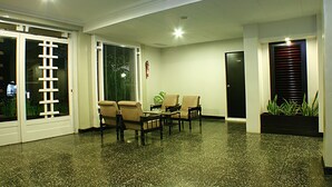 Um saguão com balcão de recepção, área de estar e uma porta com janela.
