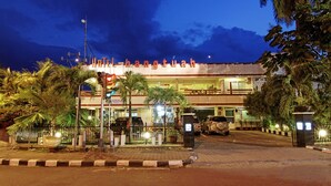 Um hotel com uma placa visível, área de estacionamento e entrada com portão.