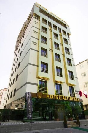 Um hotel com vários andares, entrada destacada, varandas e uma bandeira.