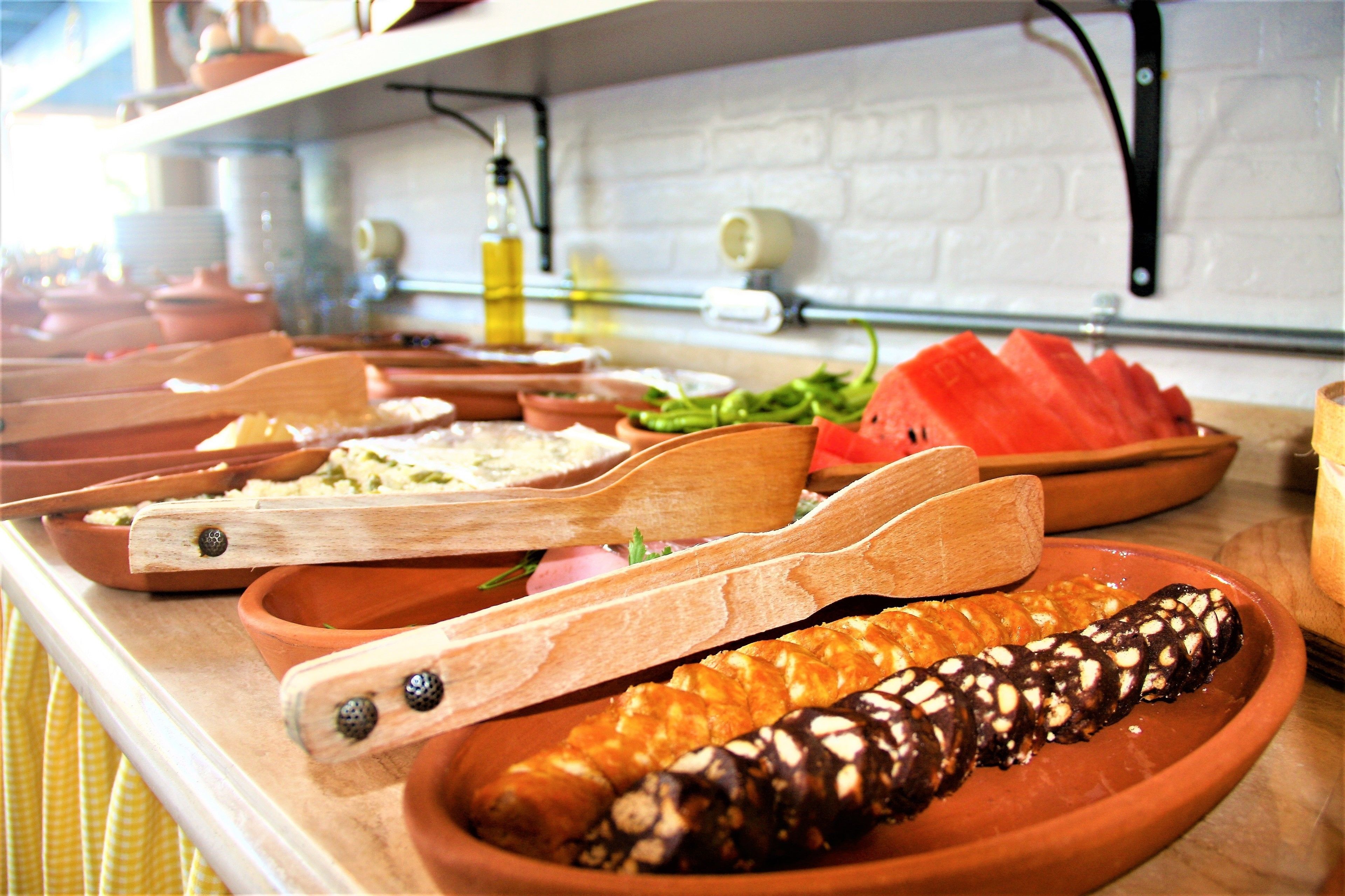 Buffet com diversos pratos e utensílios de madeira.