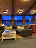 Uma sala de estar aconchegante com um sofá seccional, uma mesa de centro e grandes janelas com vista para uma paisagem nevada.