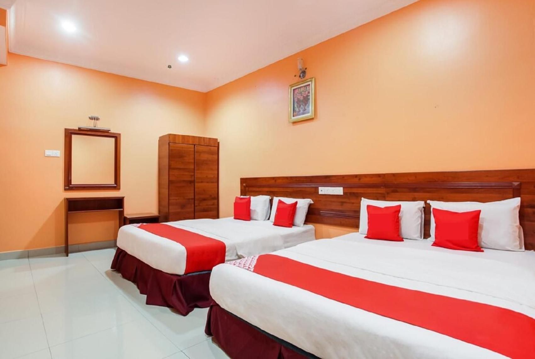 Quarto de hotel com duas camas, cabeceira de madeira, guarda-roupa, espelho e uma mesa pequena.