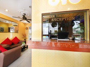 Uma área de recepção com sofá, ventilador de teto e balcão.