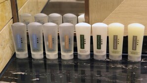 Artigos de higiene pessoal dispostos sobre um balcão de mármore preto em um hotel.