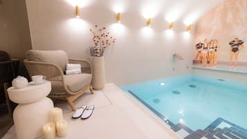 Uma área de spa com hidromassagem, cadeiras de vime, velas e luminária fixada na parede.