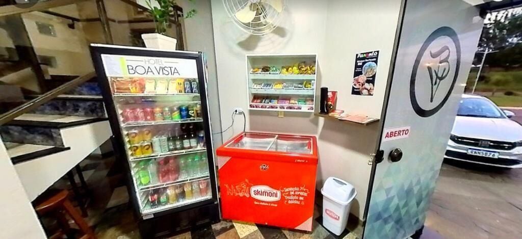Quarto de hotel com minibar, refrigerador de sorvete vermelho, lixeira e um carro estacionado do lado de fora.