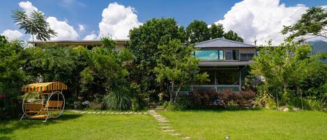 Uma casa moderna com um jardim bem cuidado, baloiço e céu limpo.