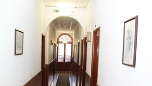 Um corredor com painéis de madeira, carpete estampado e quadros nas paredes.