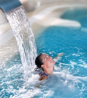 Uma pessoa em uma piscina com água saindo de um cano.