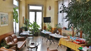 Uma sala de jantar com sofás de couro, uma mesa com toalha amarela e plantas em vasos.